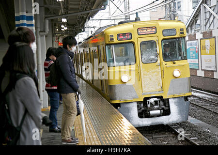 Passengers wait to aboard a yellow Seibu train at Kami-Shakujii station ...