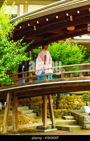 a shinto priest in traditional robes takes part in a ritual ceremony ...