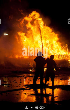 Silhouette of Firemen fighting a raging fire with huge flames of ...