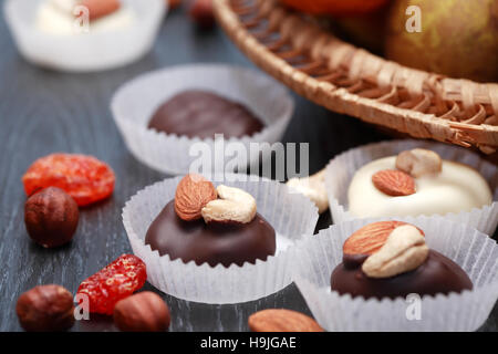 Few chocolate candies and nuts on wooden table Stock Photo - Alamy