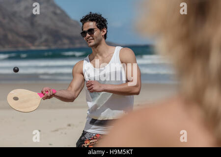 Young couple playing beach paddles on the beach Stock Photo - Alamy