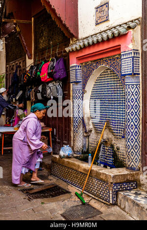 A woman collects water from a public tap following monsoon rains around ...