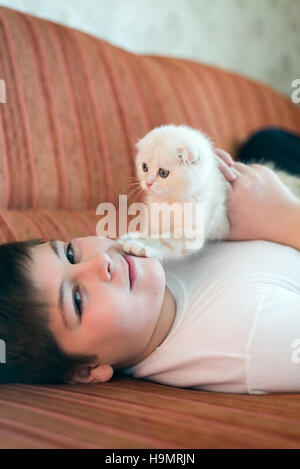 Teen boy and cat lying on carpet and watching video in smartphone Stock ...