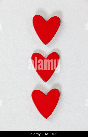 Three red hearts in a row cut from paper on white background, craft ...