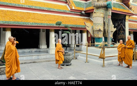A Buddhist monk wearing saffron robes cutting a log with a chainsaw ...