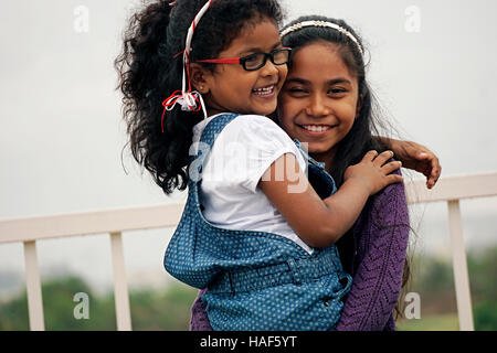 Two young Indian girls hugging a calf in a rural Indian village. Andhra ...