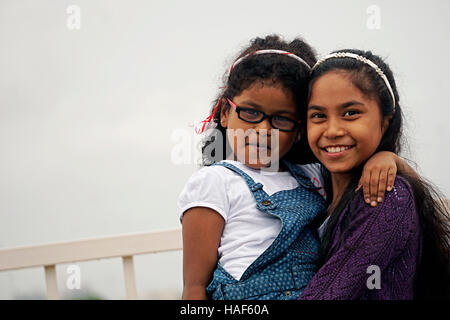 Two young Indian girls hugging a calf in a rural Indian village. Andhra ...