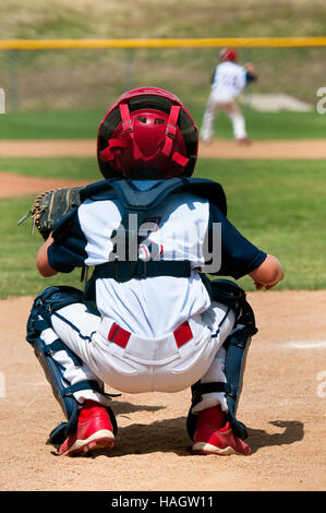 American youth baseball catcher behind home plate waiting on pitch ...