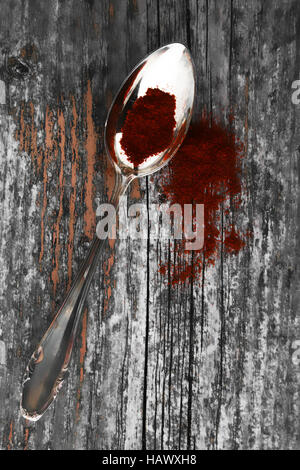 Top view of the silver spoon with chili spices on the textured blue ...