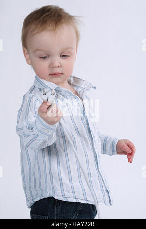 Toddler baby boy plays with electric wires while sitting on the floor ...