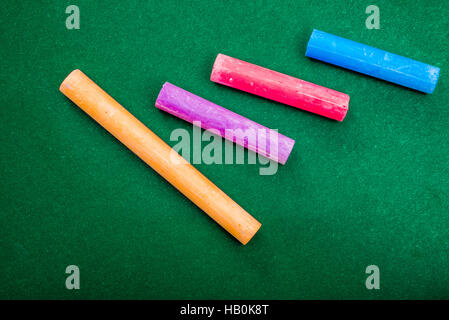 Four pieces of chalk of different bright colours and different lengths ...