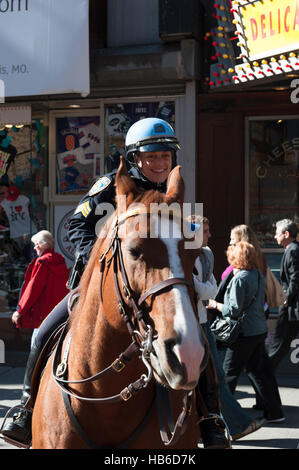 Portrait of a smiling police officer in uniform and holding a pair of ...