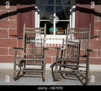 Two rustic wooden rocking chairs, weathered and worn, on the front ...