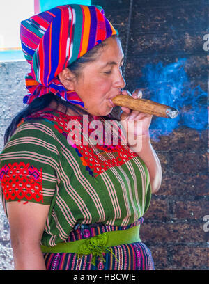 A native Guatemalan woman in traditional dress braids the hair of a ...