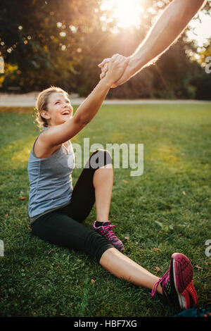 Outdoor shot of young man helping woman crossing stream. Couple in ...
