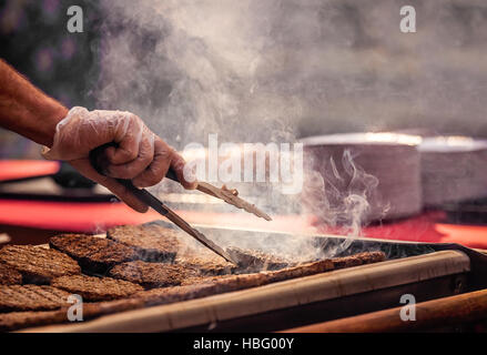 Man grilling burgers on a barbecue in a luxury glamping resort ...