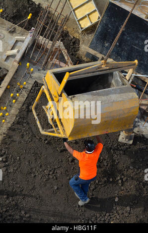 concreting work: construction site worker during concrete pouring into ...