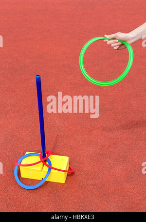 Arm throwing colored rings around tube Stock Photo - Alamy