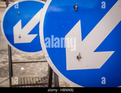 Two blue round road signs indicating on which on the lines you have to ...