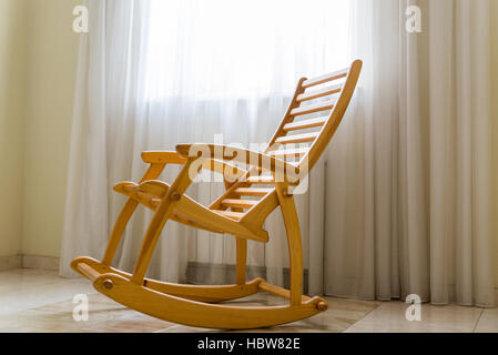 Wooden rocking chair near the window in room Stock Photo - Alamy
