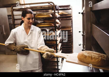 Female baker baking fresh bread in the bakehouse Stock Photo - Alamy