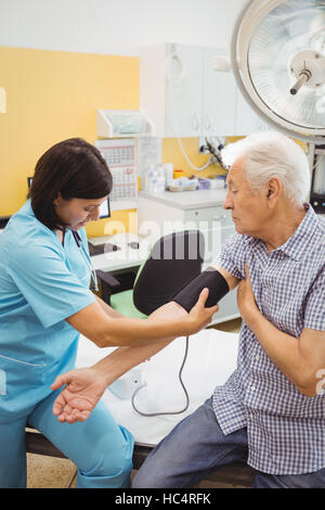 Doctor checking blood pressure of mature female patient at clinic Stock ...