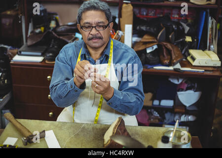 shoemaker putting thread in the needle in workshop Stock Photo - Alamy
