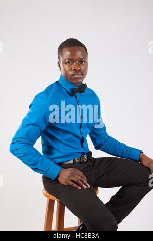 Handsome man sitting on stool against white background Stock Photo - Alamy