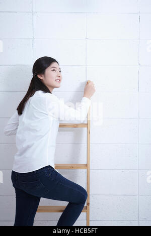 Girl looking camera while climbing ladder Stock Photo - Alamy
