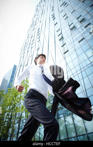Low angle view of young businessman in suit holding laptop and shaking ...