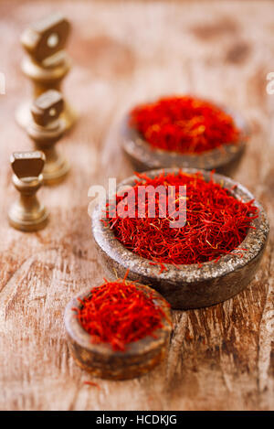 saffron spice in antique vintage iron bowls weights on wooden table ...