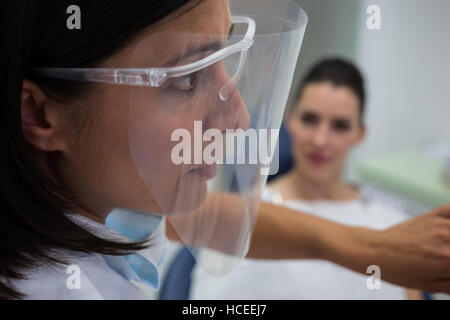 Dentist, dental hygienist, wearing a face mask and magnifying loupes ...