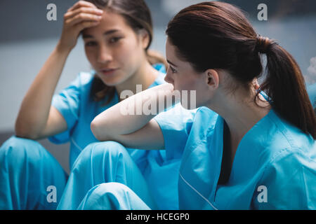 Sad nurses sitting on corridor Stock Photo - Alamy