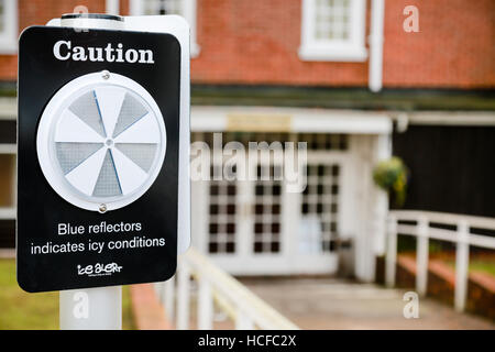 A high tech sign warning about icy conditions on a sloping surface ...