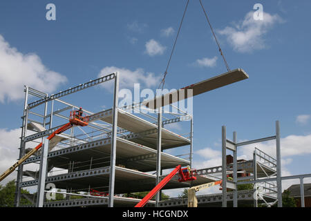 PPE equipped construction worker in cherry picker fitting PCC precast ...