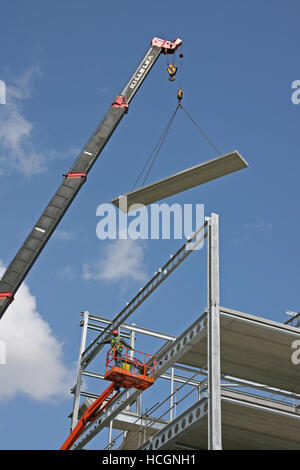 PPE equipped construction worker in cherry picker fitting PCC precast ...