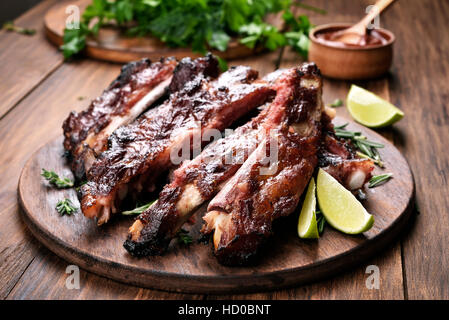 Barbecue pork ribs on wooden serving board on picnic table outdoors ...