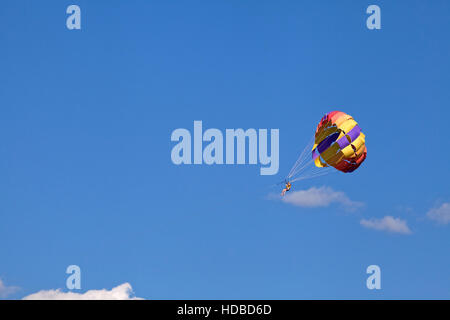Parasailing in the blue sky near the beach. Paragliders flying high in ...