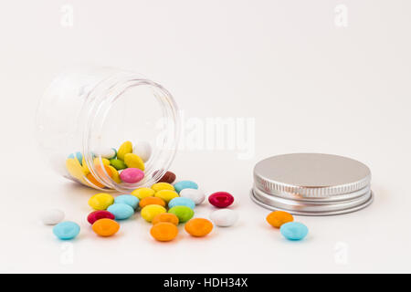 Colored Smarties scattered out of an open glass jar, isolated on white ...