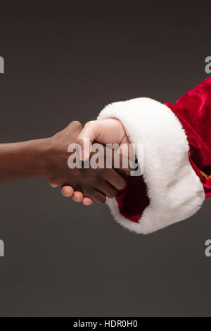 The handshake of Santa Claus hand and hand of african man. Merry ...
