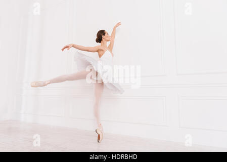 Ballerina posing on tiptoes with her arms raised and back bent back ...