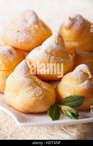 Golden baked eclairs on white ceramic plate. Rustic wood surface with ...