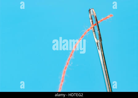 Red thread, being threaded through a needle Stock Photo - Alamy