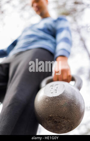 Closeup of man holding heavy kettlebell at gym with blurred background ...