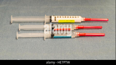Three syringes with red capped needles containing labeled generic ...