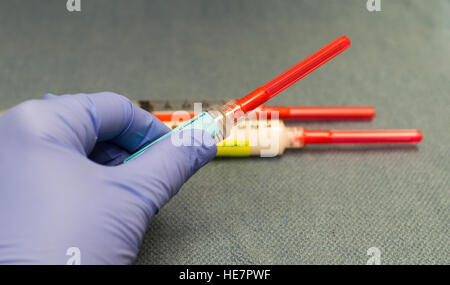 Three labeled syringes with red capped safety needles containing drugs ...