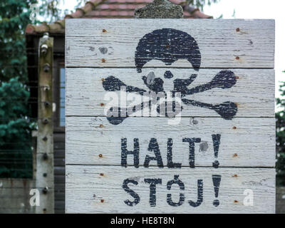 Warning sign with a skull (stop) in front of a barbed wire in Auschwitz ...