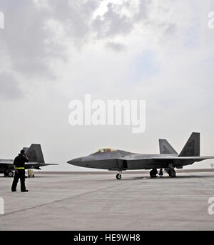 An F-22 Raptor crew chief from the 154th Wing marshals an F-22 at Royal ...