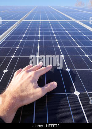 Hand touching solar panel cells in a renewable energy setting during ...