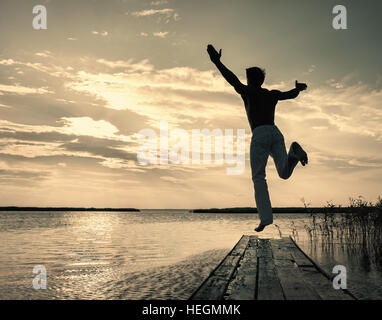 Man jumping off wooden jetty into sea Stock Photo - Alamy